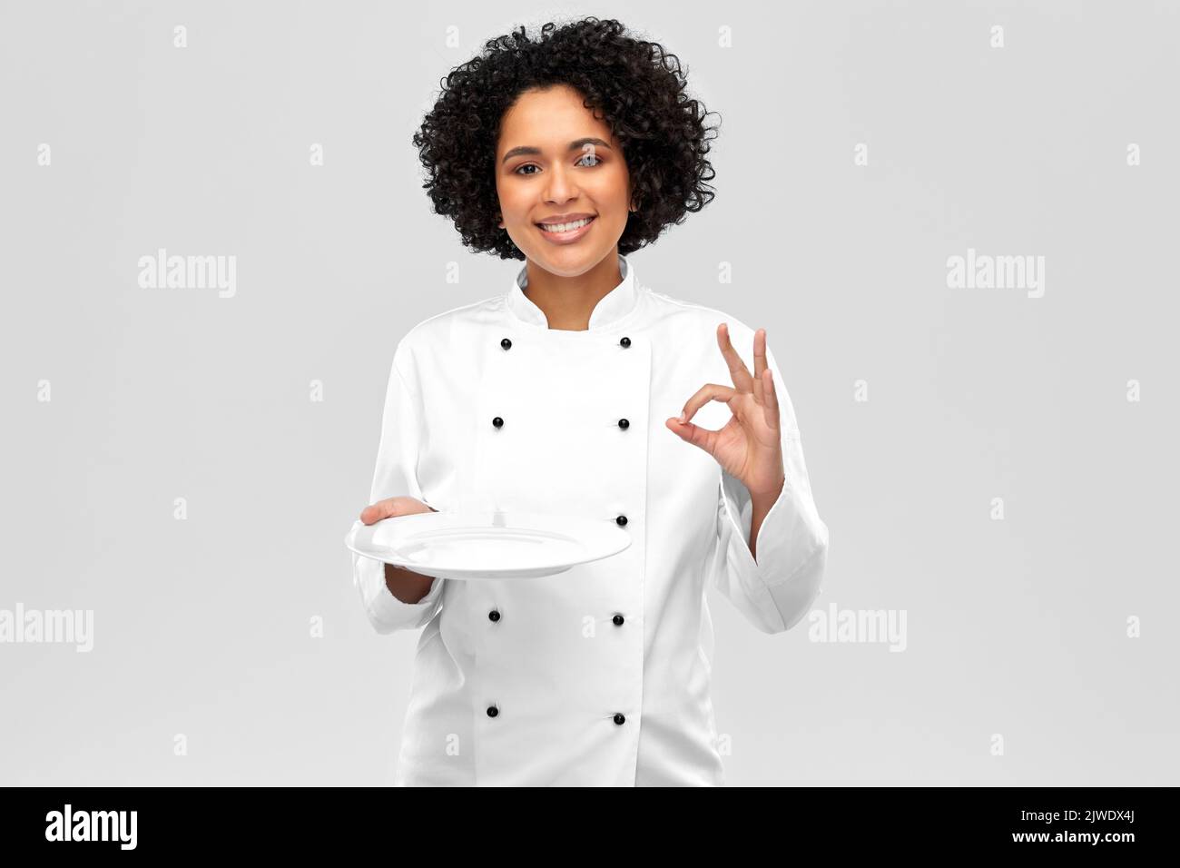 female chef holding plate and showing ok sign Stock Photo - Alamy