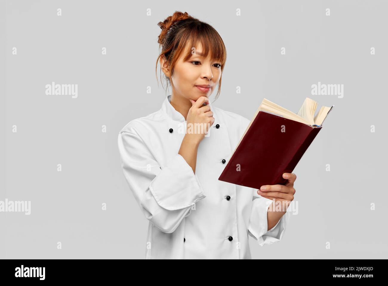 thinking female chef reading cook book Stock Photo - Alamy