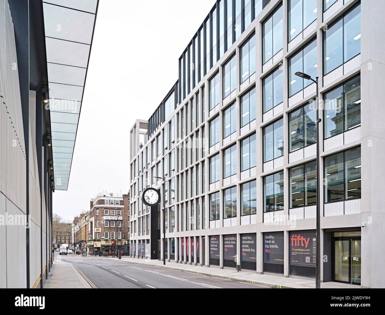 Street view along glazed building facade with large exterior clock. 50 ...