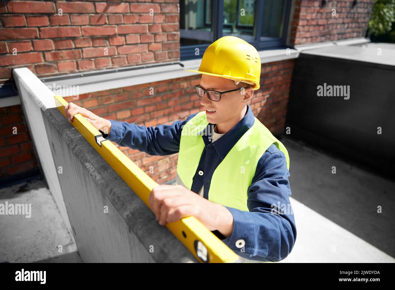male builder with level measuring wall Stock Photo - Alamy