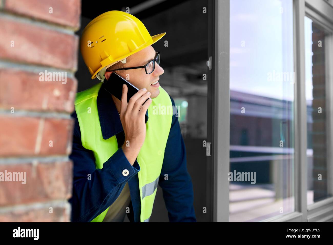 builder looking out window and calling on phone Stock Photo - Alamy