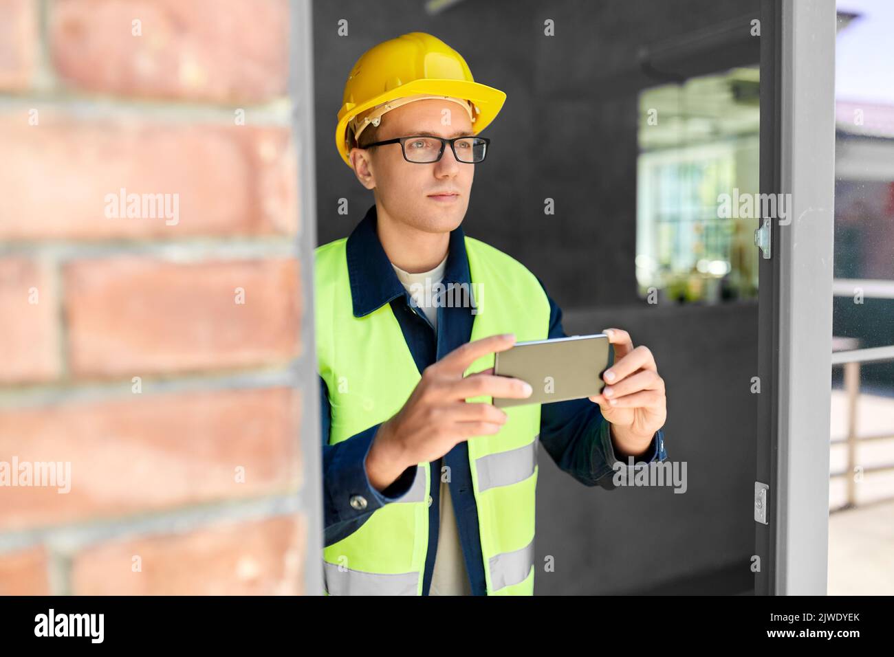 builder with smartphone taking picture at window Stock Photo - Alamy
