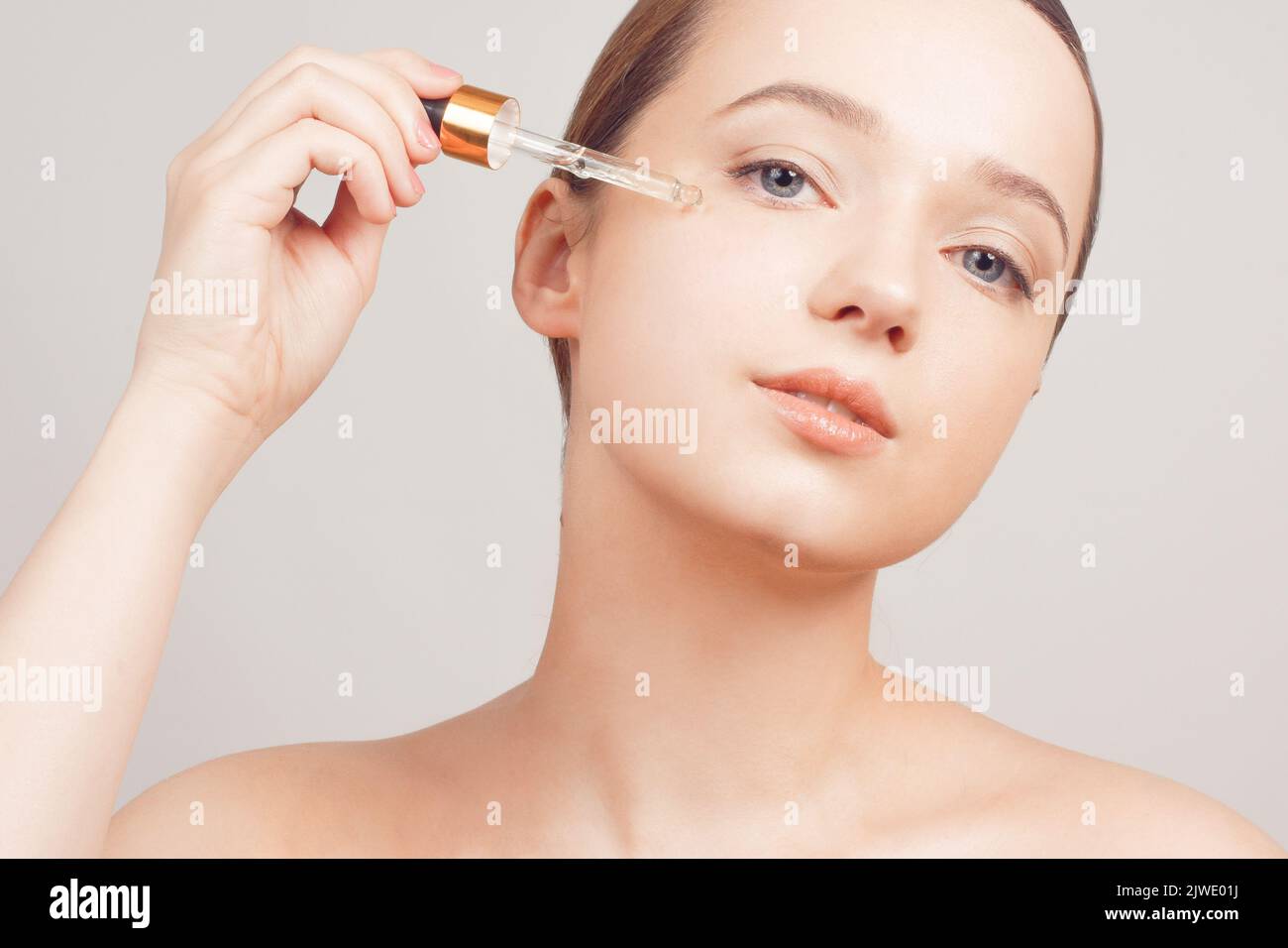 Girl on a white background skin care, oil, serum with a pipette on her ...