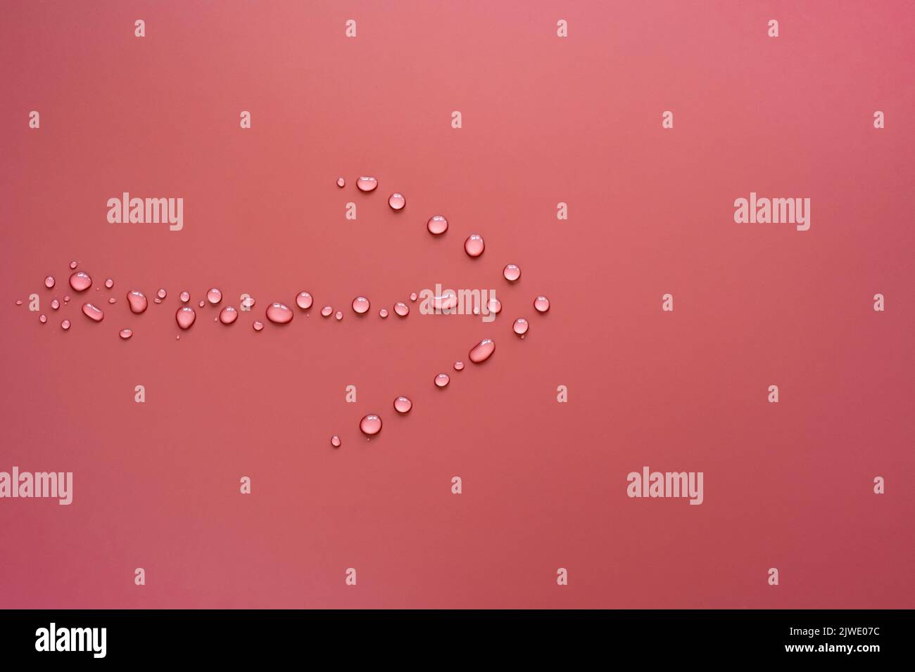 Arrow from drops of pure water, on a pink background. Sign showing the ...