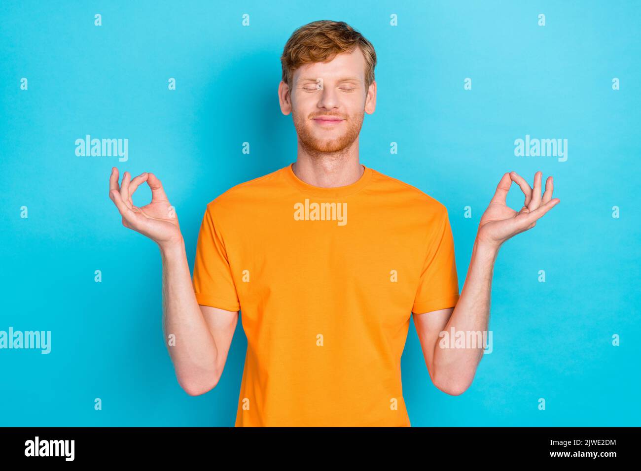 Photo of meditate red hair guy wear orange t-shirt isolated on teal ...