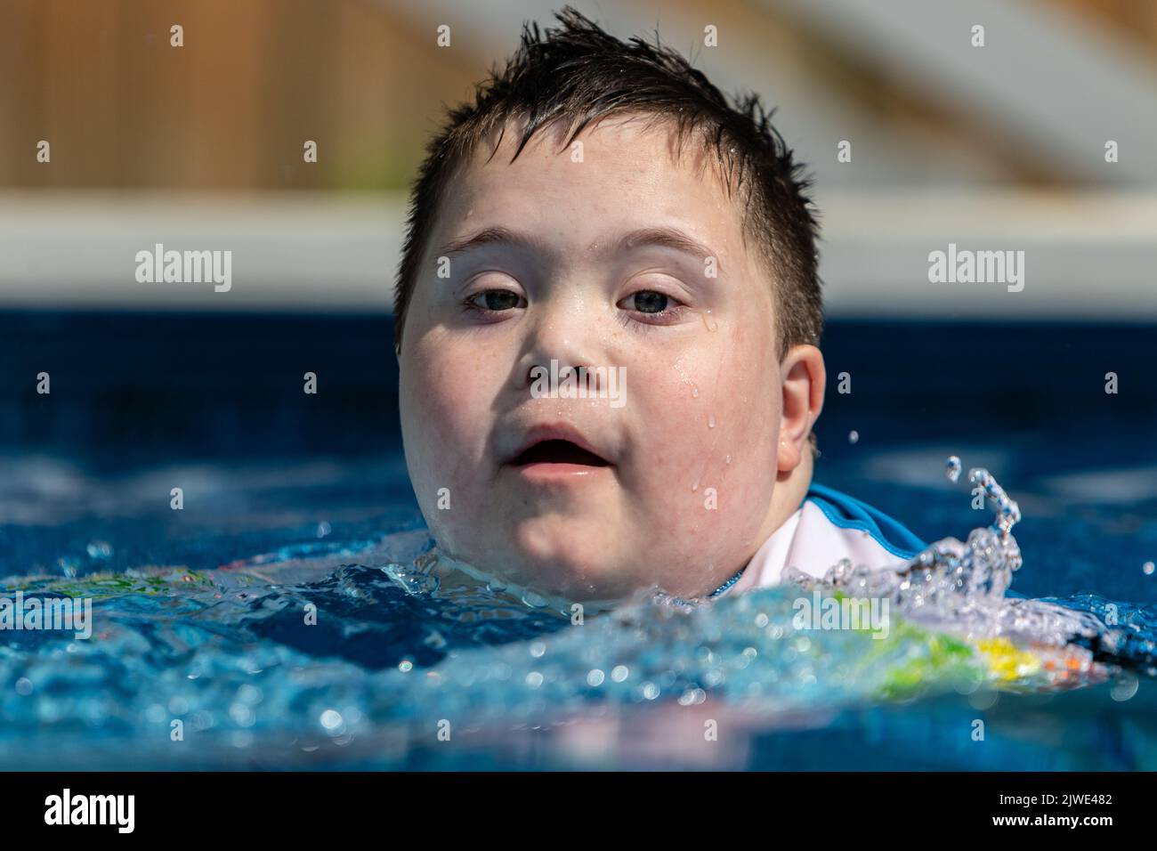 Close up of a boy with Down Syndrome swimming in a pool Stock Photo - Alamy