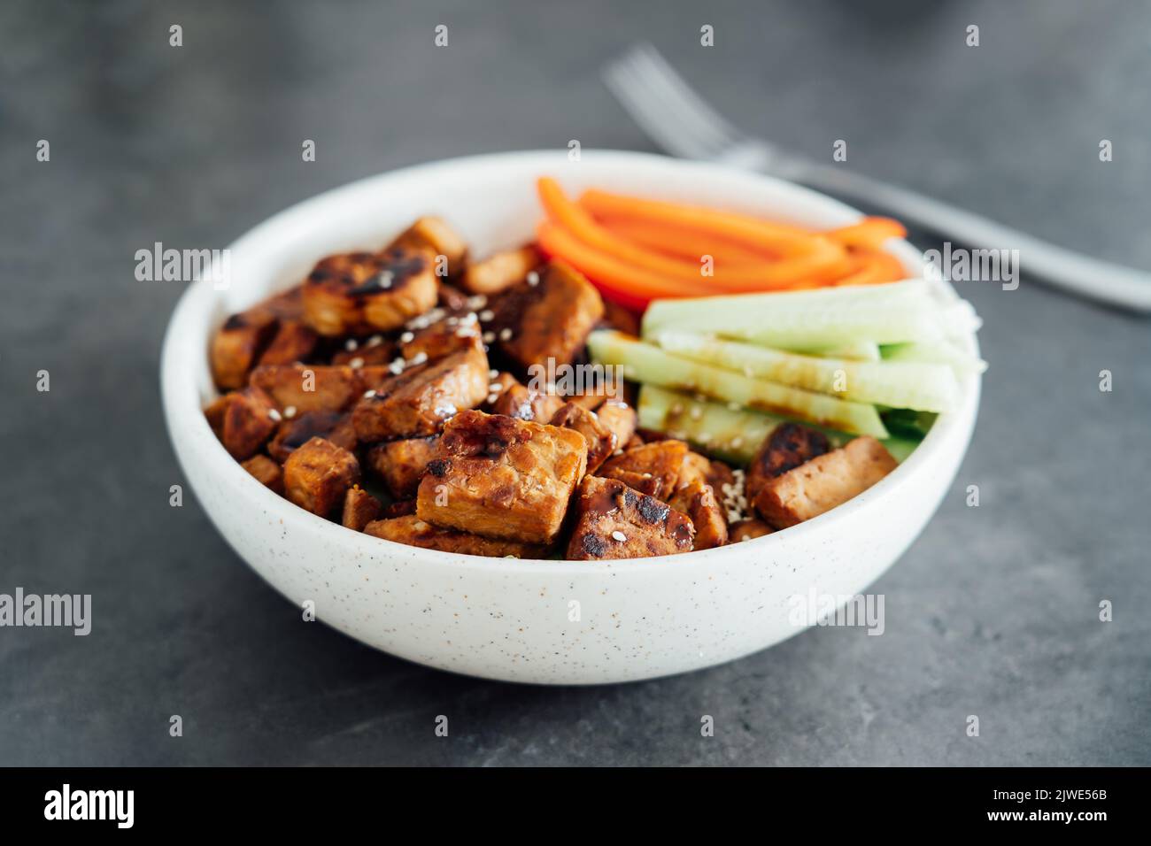 Bowl with roasted tempeh made of fermented soy beans, fresh vegetable ...