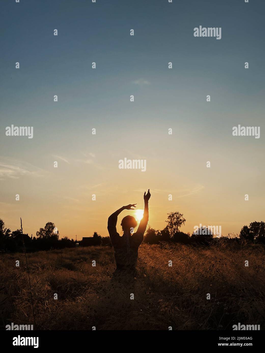 Silhouette of a woman dancing in a field at sunset, Belarus Stock Photo ...