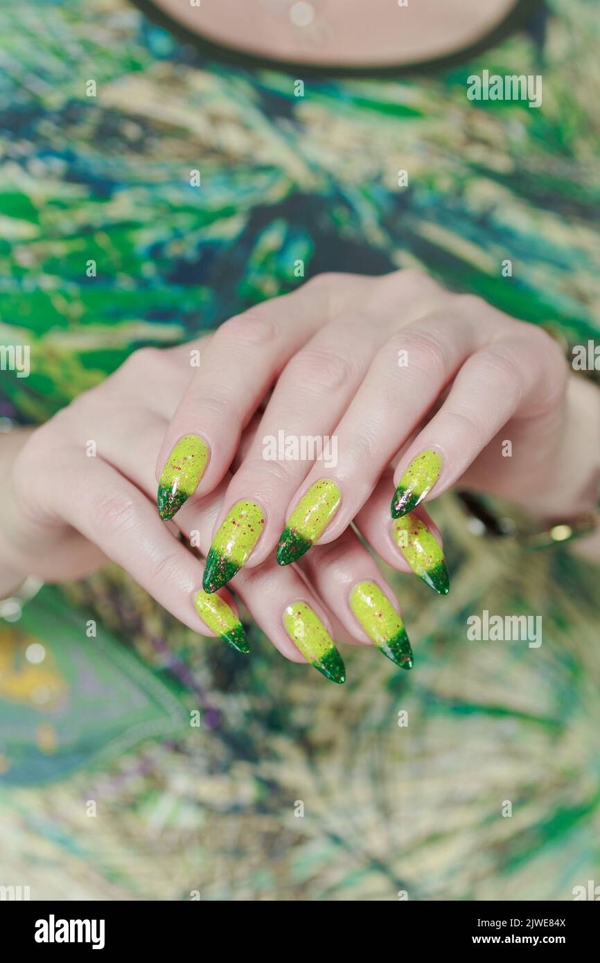 Woman's hand with long nails and bright yellow green thermo manicure ...