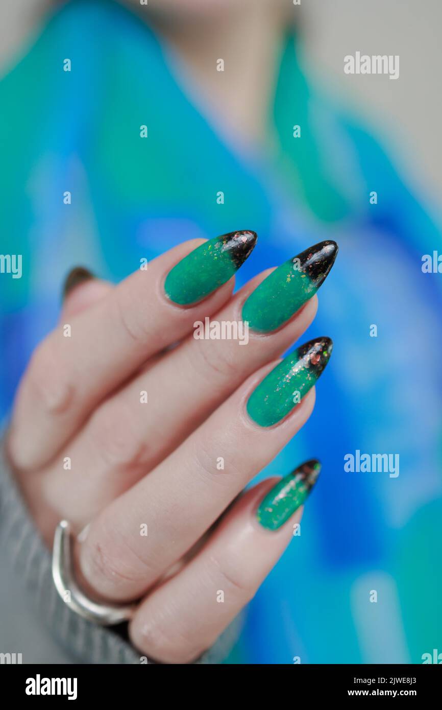Female hand with long nails and green-black thermo french nail polish ...