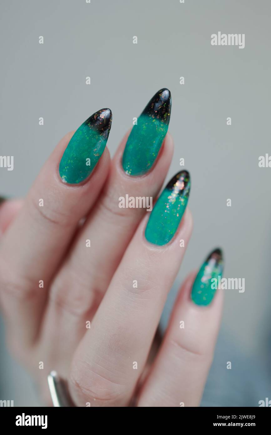 Female hand with long nails and green-black thermo french nail polish ...