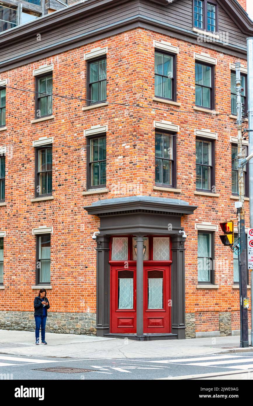 A woman stands in front of the Bishop's Block old heritage brick ...