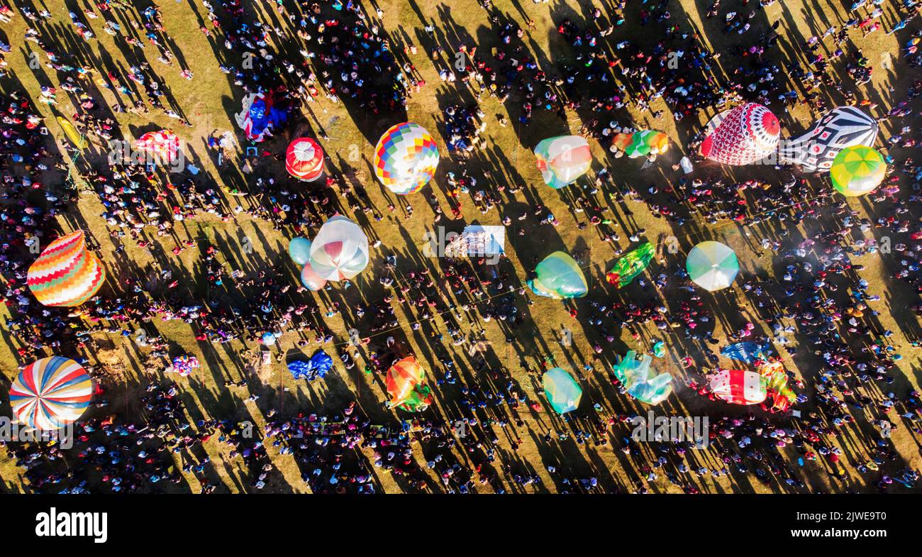Aerial view of crowds of people and hot air balloons on ground at a ...