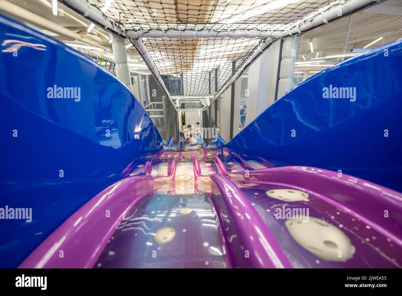 Two parallel purple sliders with blue barriers at playground inside the ...
