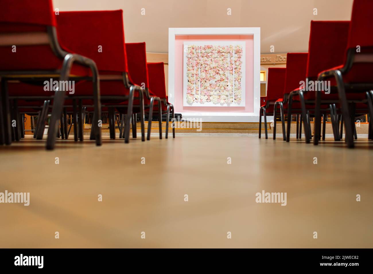 hall and empty stage, many rows of red chairs and festive velvet stage ...