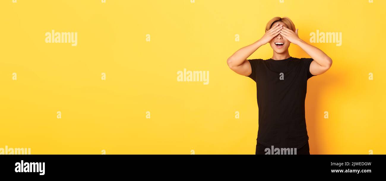 Portrait of amused and excited smiling blond guy shut eyes with palms ...
