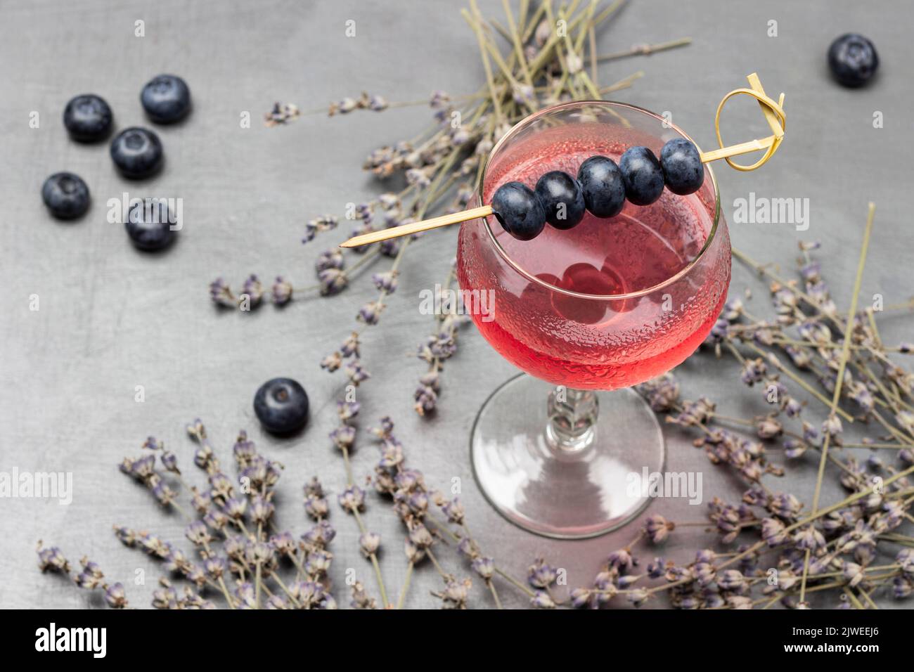 Blueberries on skewer. Wine glass with cooling drink. Drops of water on ...