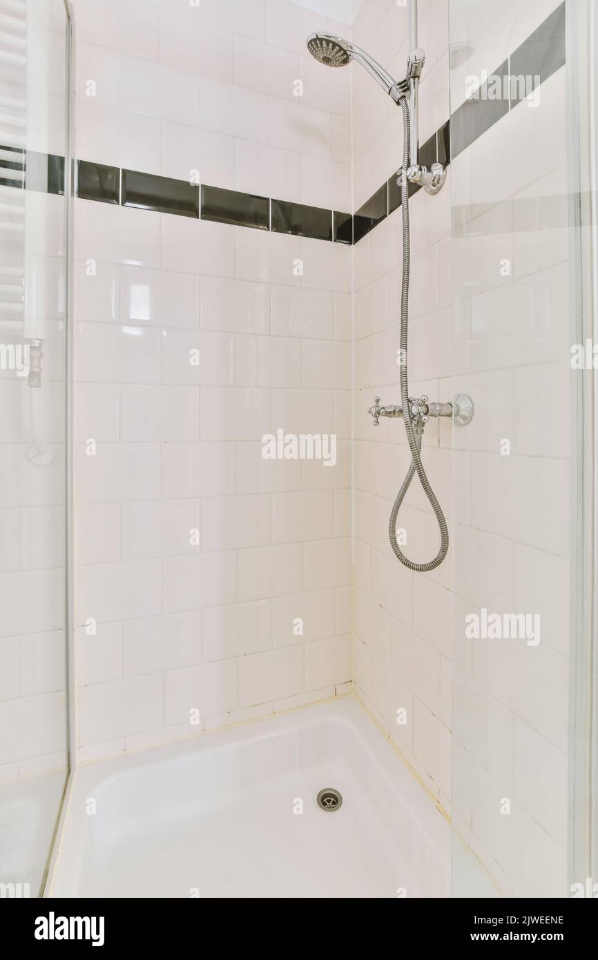 Shower faucets attached to tiled wall near glass partition and ...