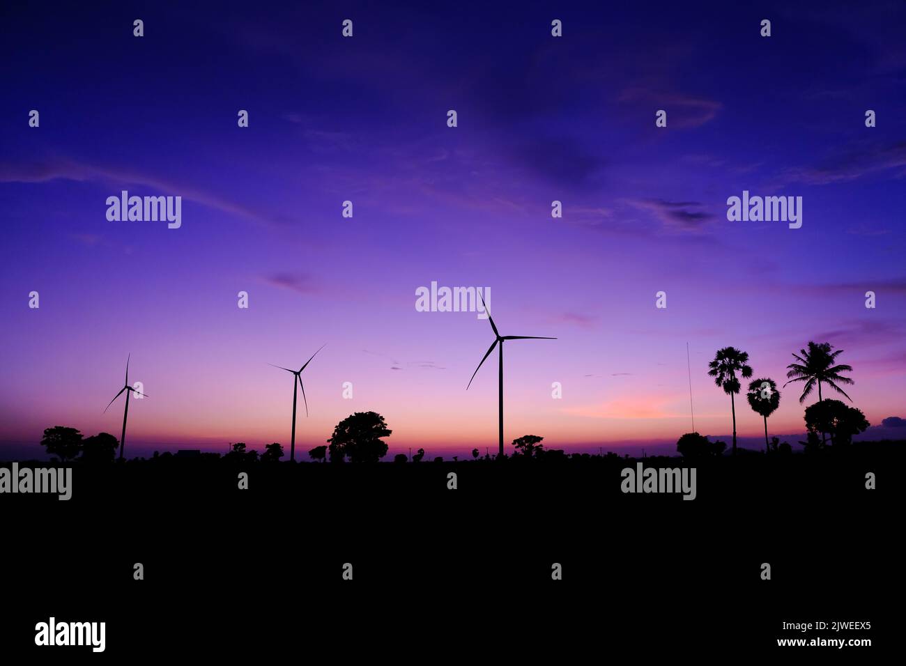 Silhouette of three wind turbines in a field at sunset, Jeneponto ...