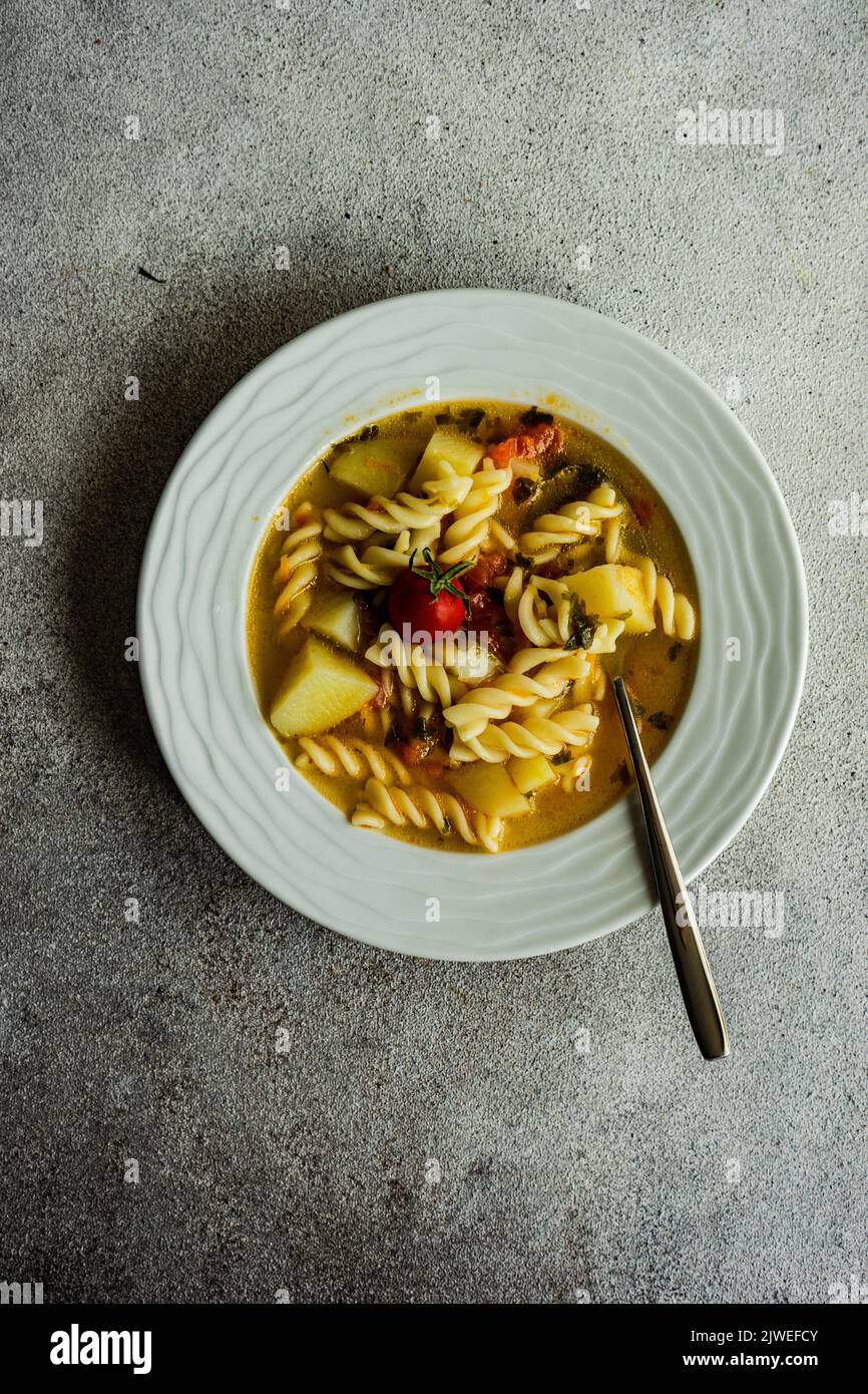 Overhead view of a bowl of homemade pasta, potato, tomato and vegetable ...