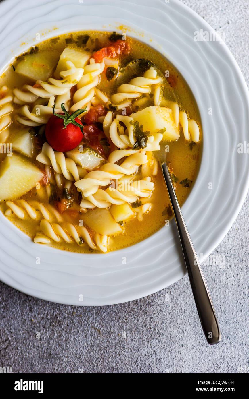 Overhead view of a bowl of homemade pasta, potato, tomato and vegetable ...