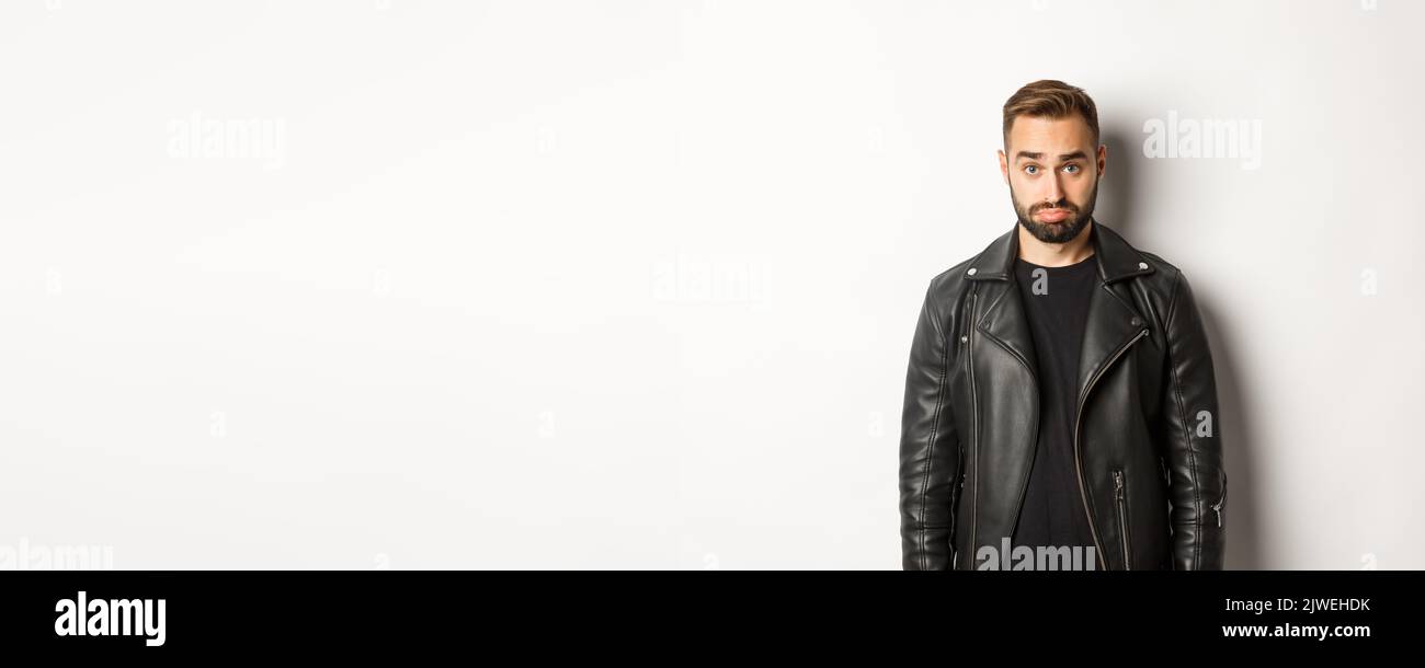 Sad and cute guy in leather black jacket pouting, looking silly at ...