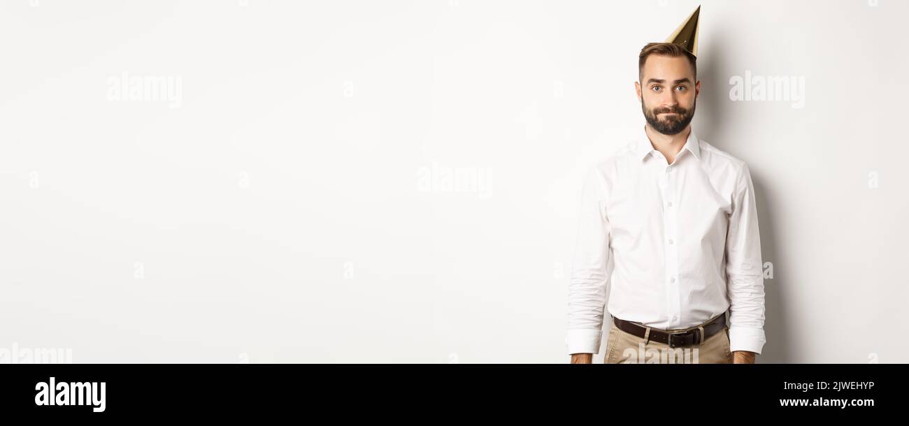 Celebration and holidays. Gloomy guy in birthday hat standing awkward ...