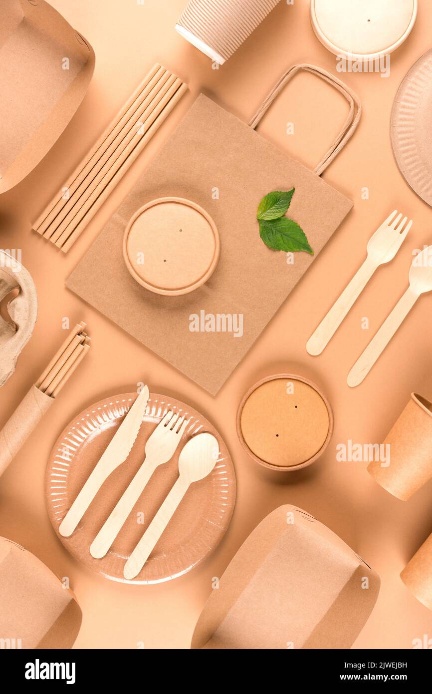 Paper utensils and wooden cutlery set over light brown background ...