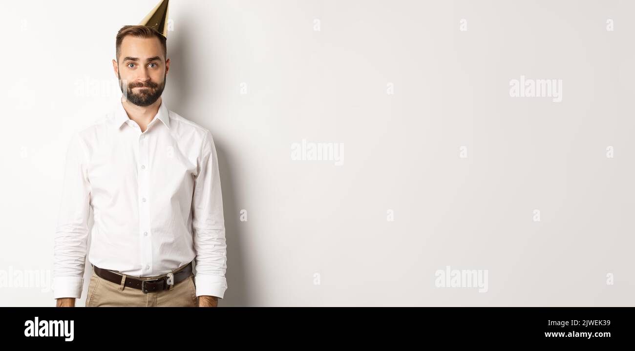 Celebration and holidays. Gloomy guy in birthday hat standing awkward ...