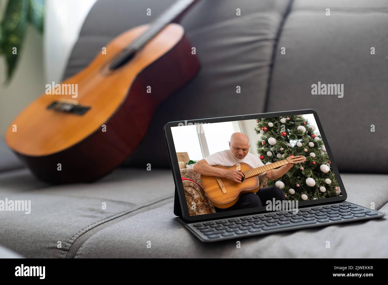 Acoustic guitar and digital tablet on a couch at cozy home background ...