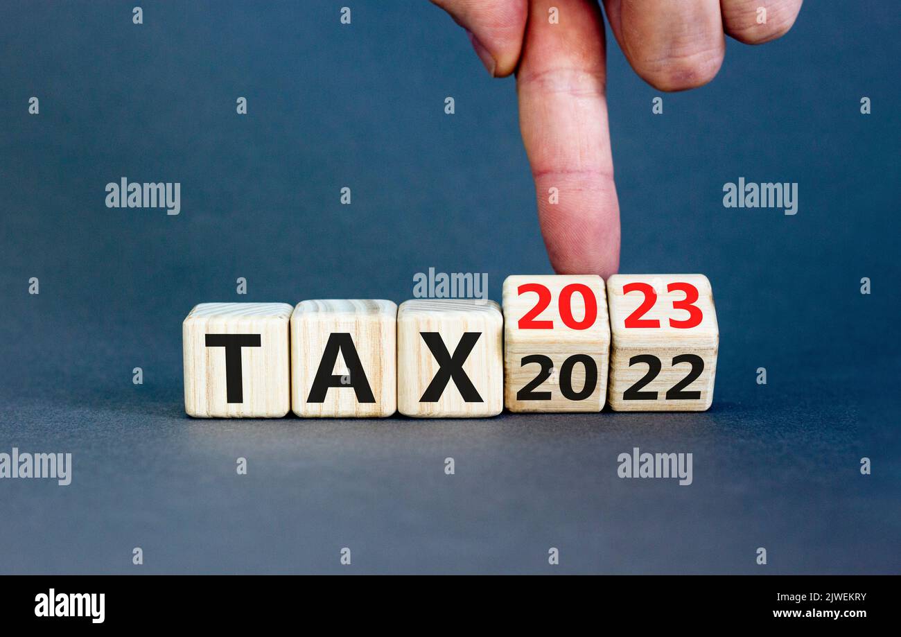 2023 tax new year symbol. Businessman turns a wooden cube and changes ...