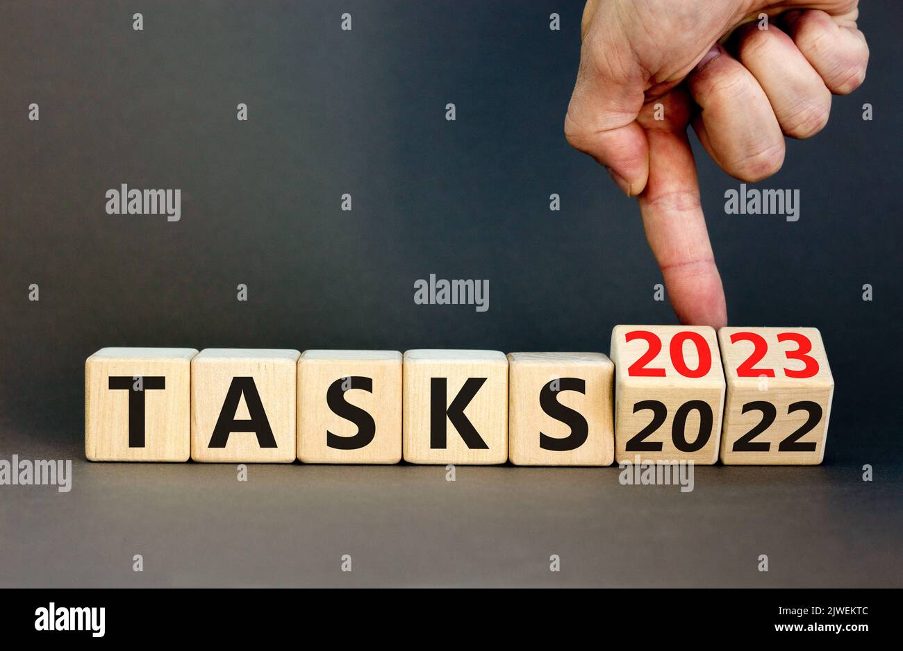 2023 tasks new year symbol. Businessman turns a wooden cube and changes words Tasks 2022 to ...