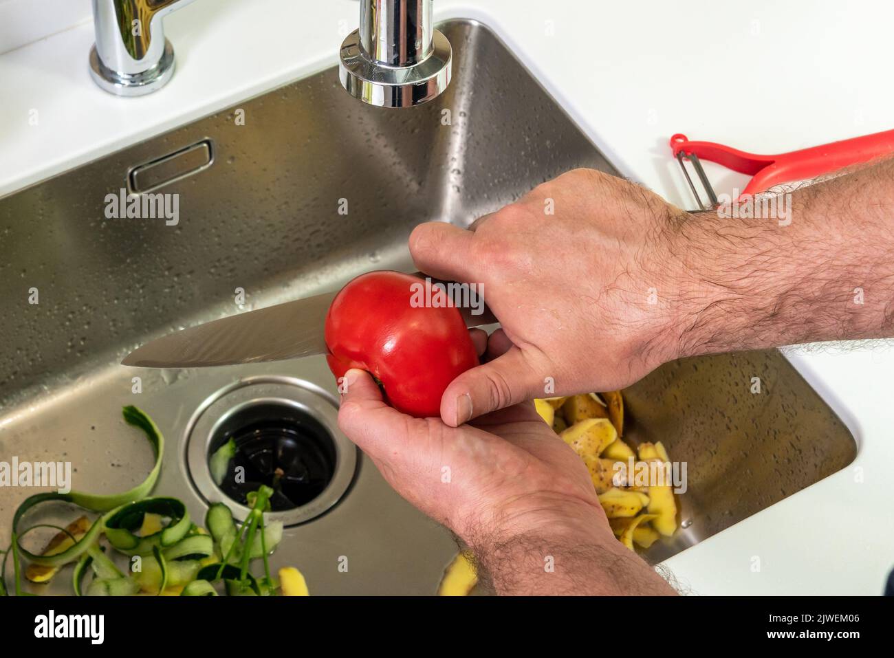 Knife cuts tomato, cleaning and cutting fresh vegetables in the kitchen ...