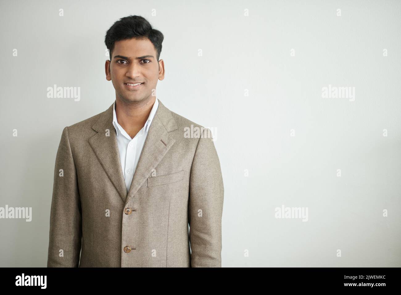 Portrait of positive elegant entrepreneur standing against light wall ...