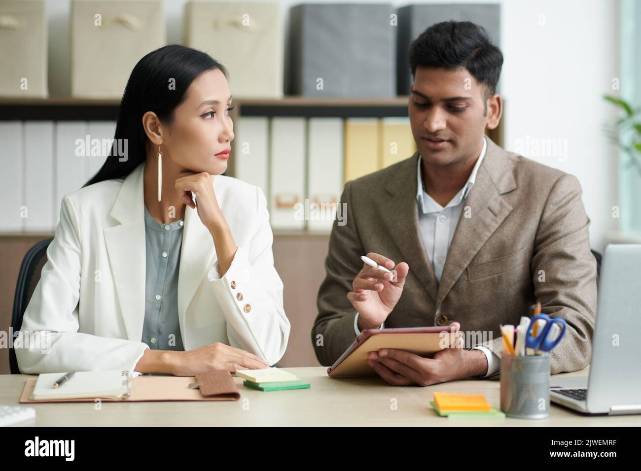 Young Indian entrepreneur asking assistant to correct some details in ...