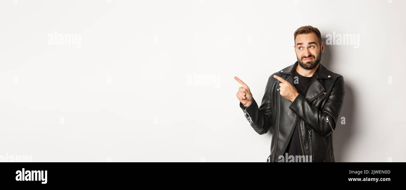 Skeptical and doubtful guy in black leather jacket, shrugging while ...