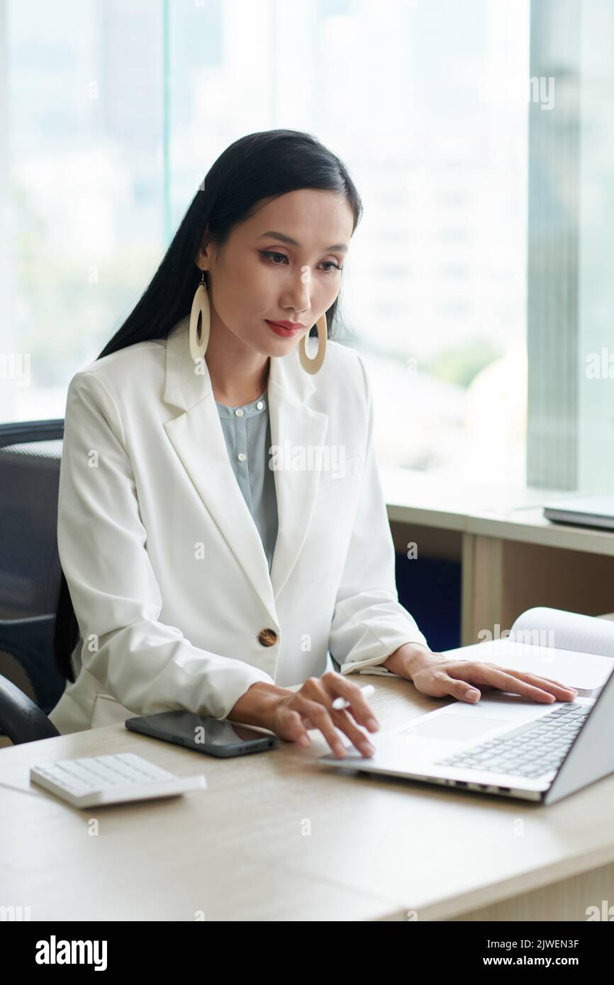 Portrait of concentrated elegant Vietnamese entrepreneur working on ...