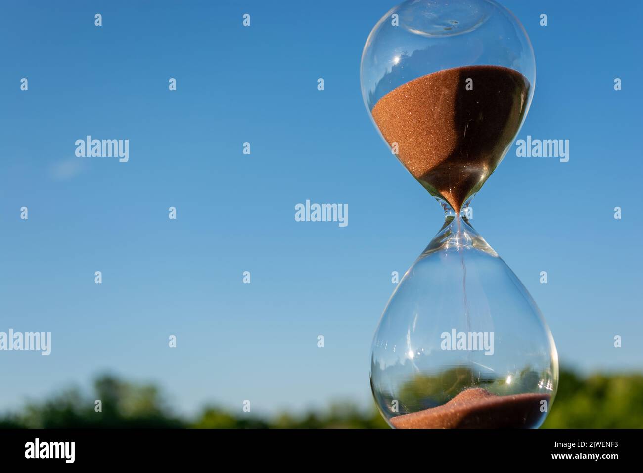 Hourglass against the blue sky on a sunny day. Changeable weather ...