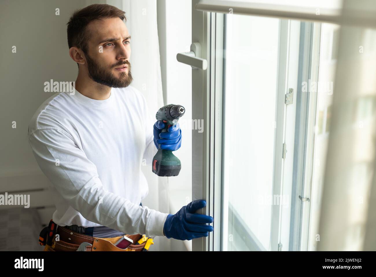 handsome young man installing bay window in a new house construction ...