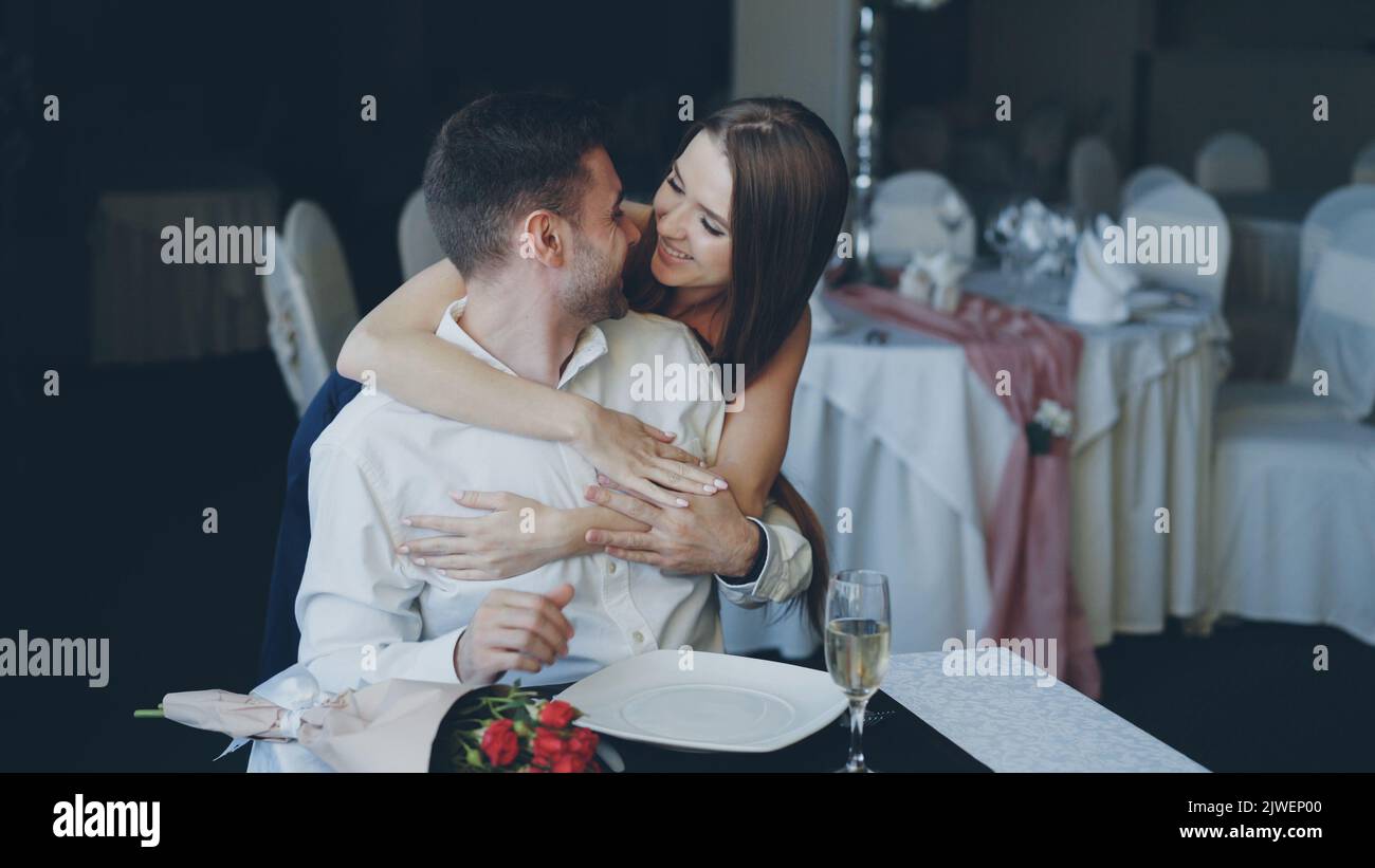 Pretty young woman is greeting her boyfriend in restaurant hugging him ...