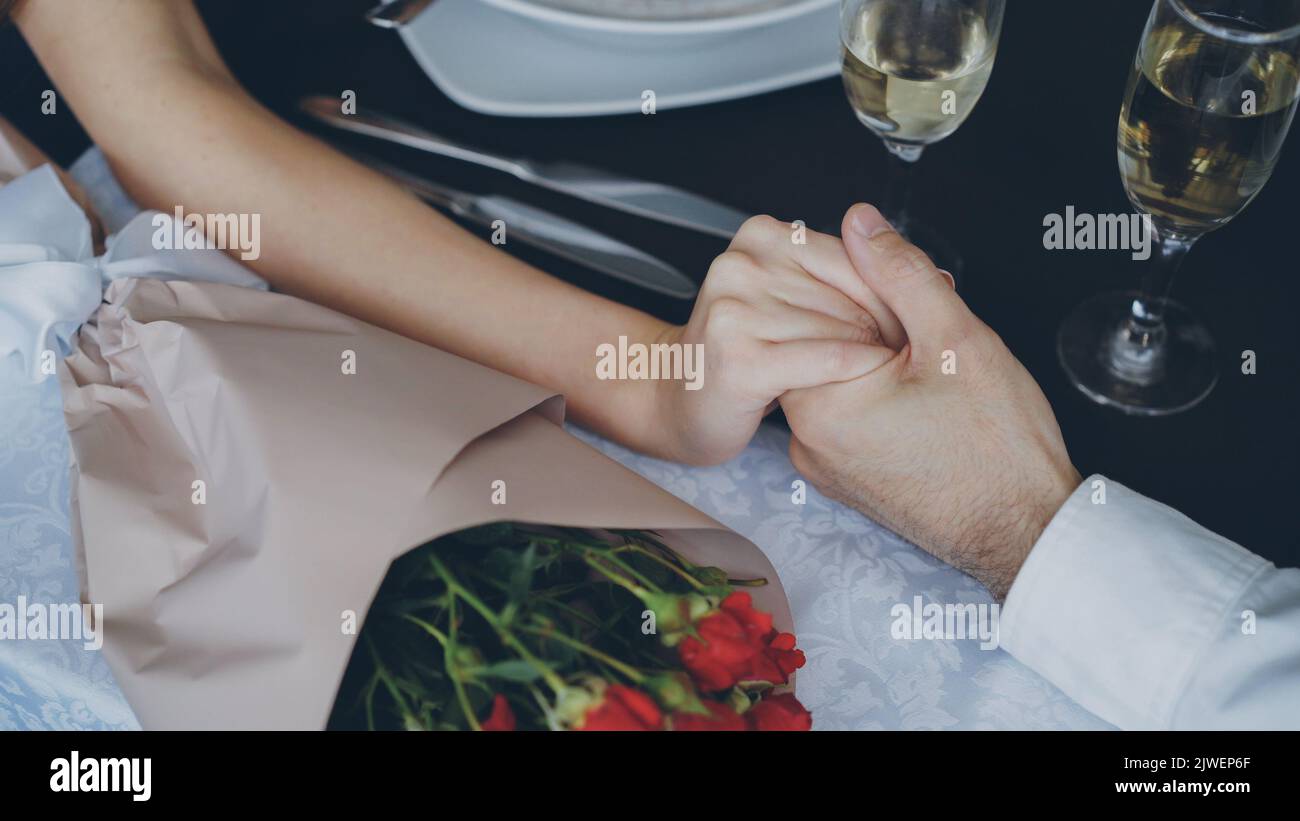 Close-up shot of male hand holding and squeezing manicured female hand ...