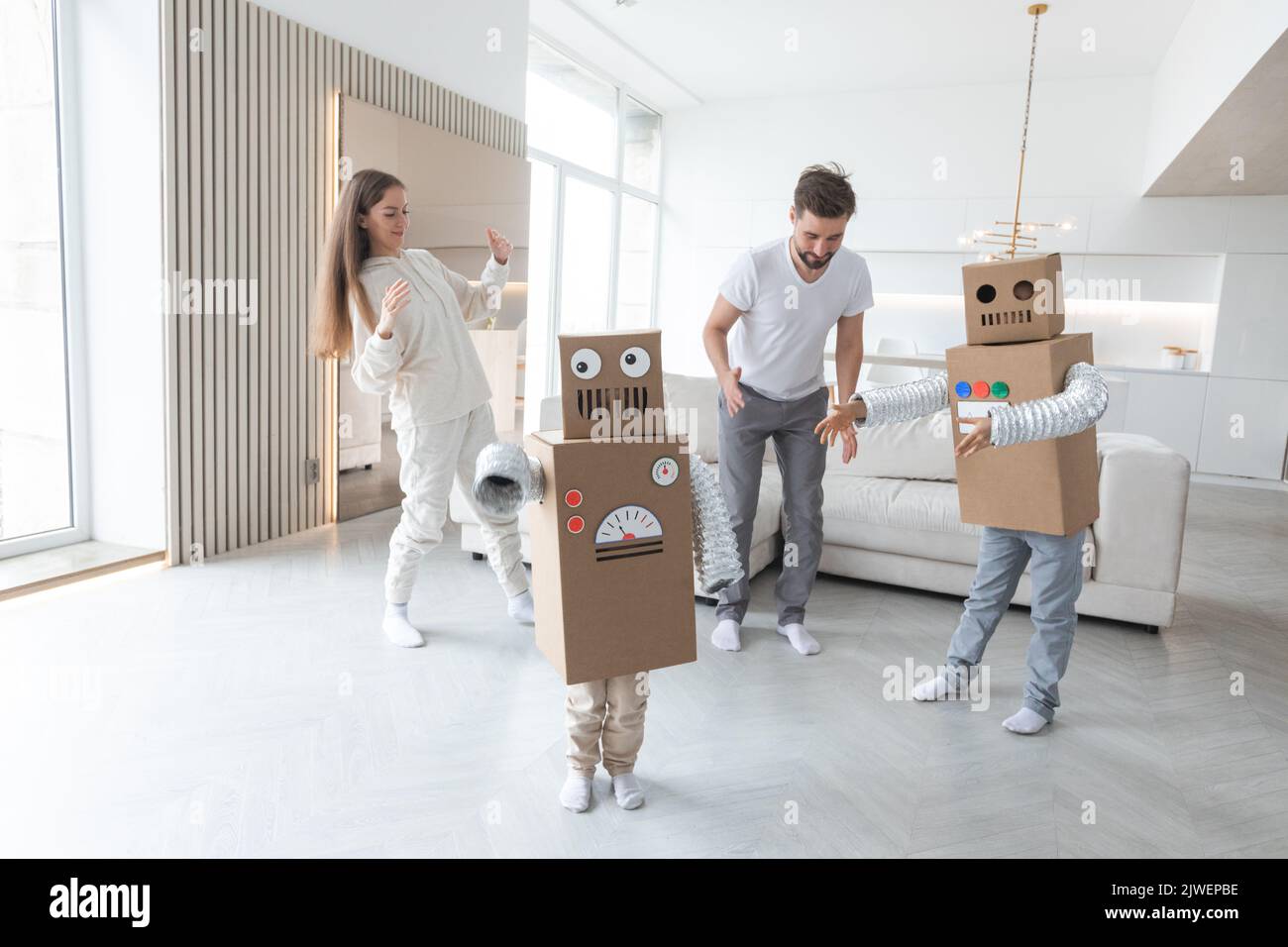 Happy family of parents and two children playing dancing like robots at ...