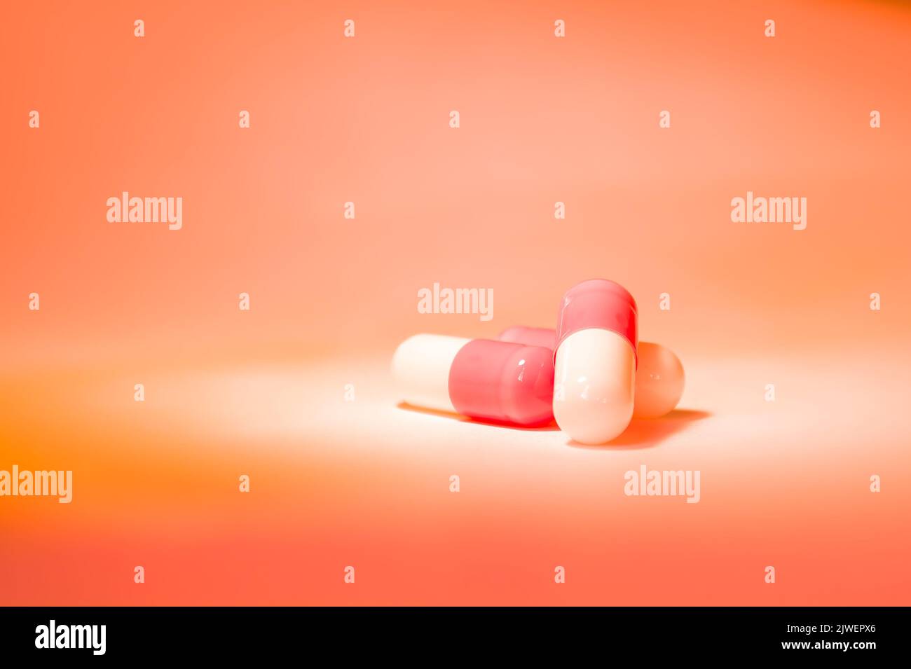 Three red white pill capsules in a slide on an orange background with a ...