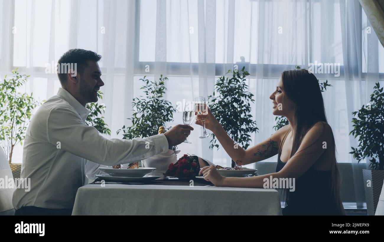 Young attractive people happy couple are clinking glasses and drinking ...
