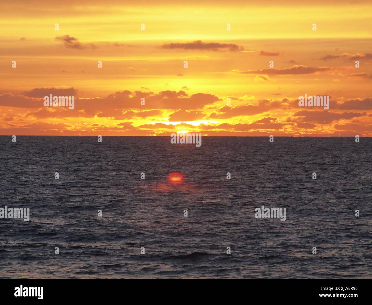 Sunrise along the New Jersey shoreline with a silhouetted container ...