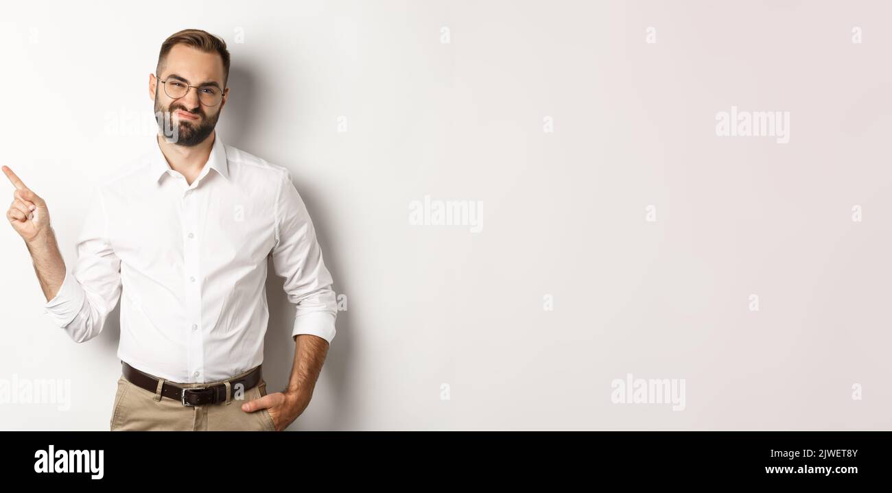 Skeptical male entrepreneur grimacing, pointing finger left with ...