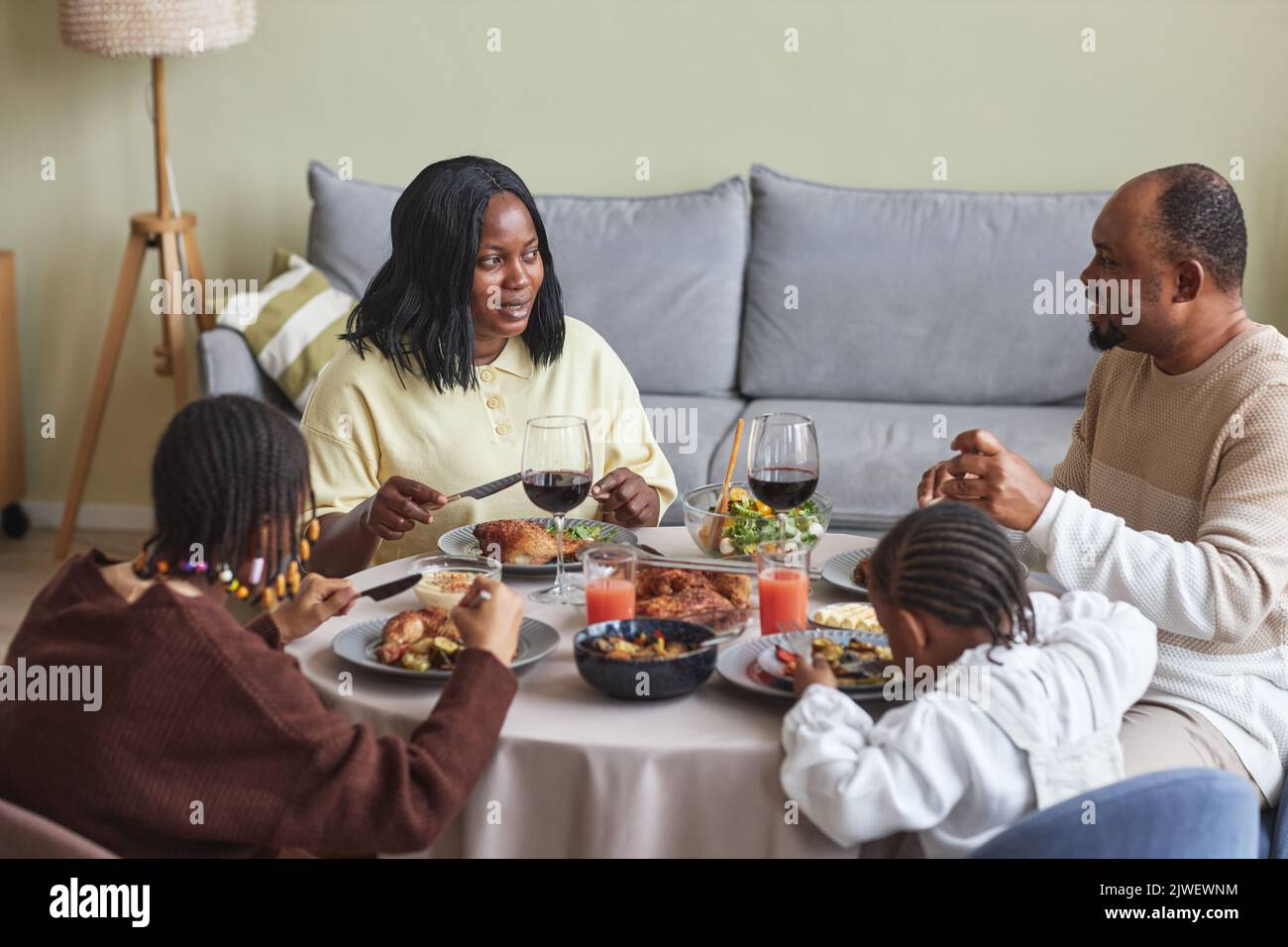 African family sitting at dining table eating and talking during ...