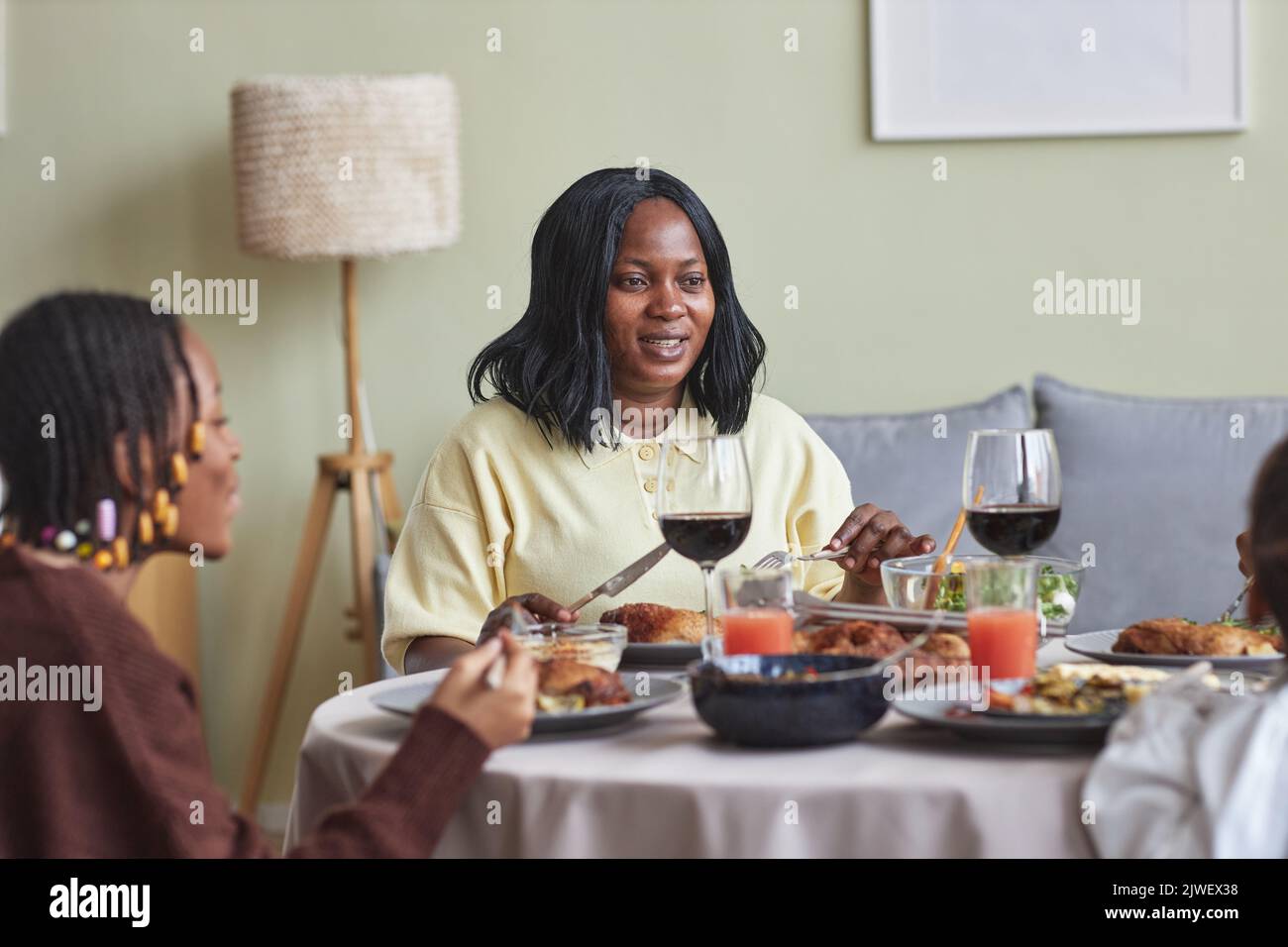 African young woman sitting at dining table with her children and ...