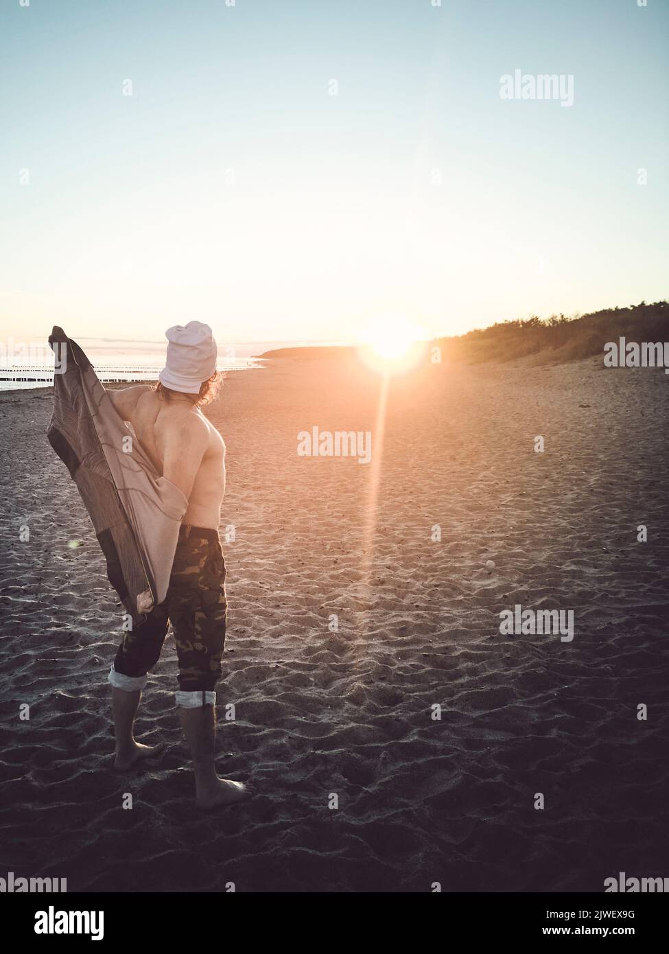 Man standing on the beach looking into sun Stock Photo - Alamy