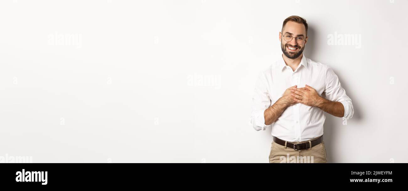 Touched and thankful business man holding hands on heart, smiling ...